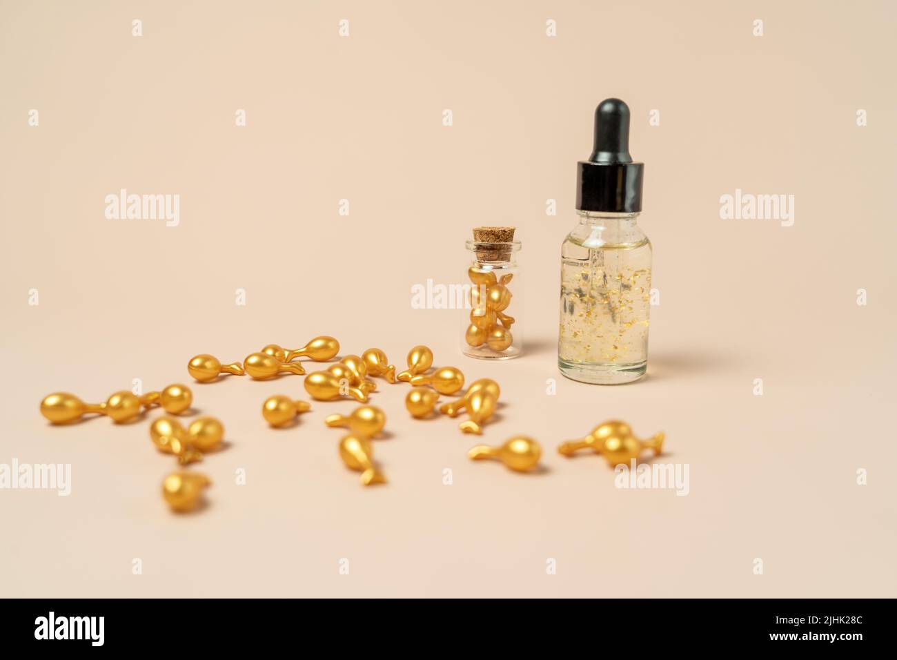 A face serum or oil in golden capsules lying on a beige background ...