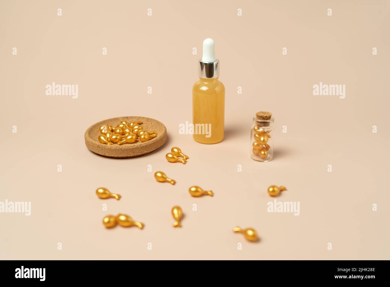 A face serum or oil in golden capsules lying on a beige background ...