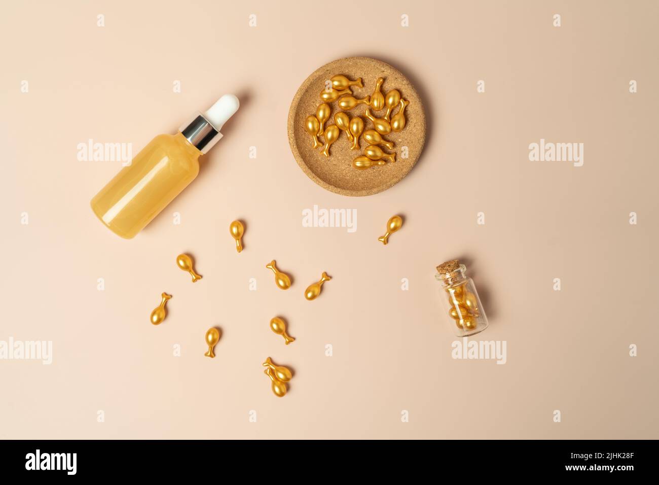 A face serum or oil in golden capsules lying on a beige background ...