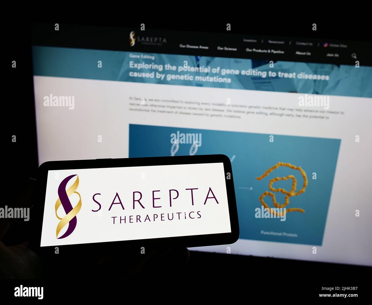 Person holding cellphone with logo of US company Sarepta Therapeutics ...