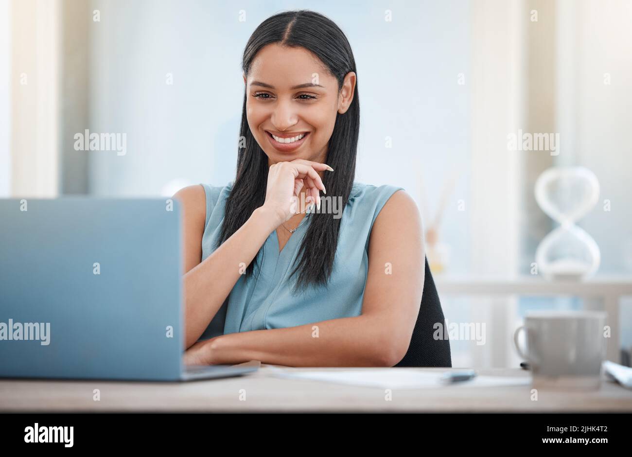 Happy young mixed race businesswoman smiling while enjoying working on ...