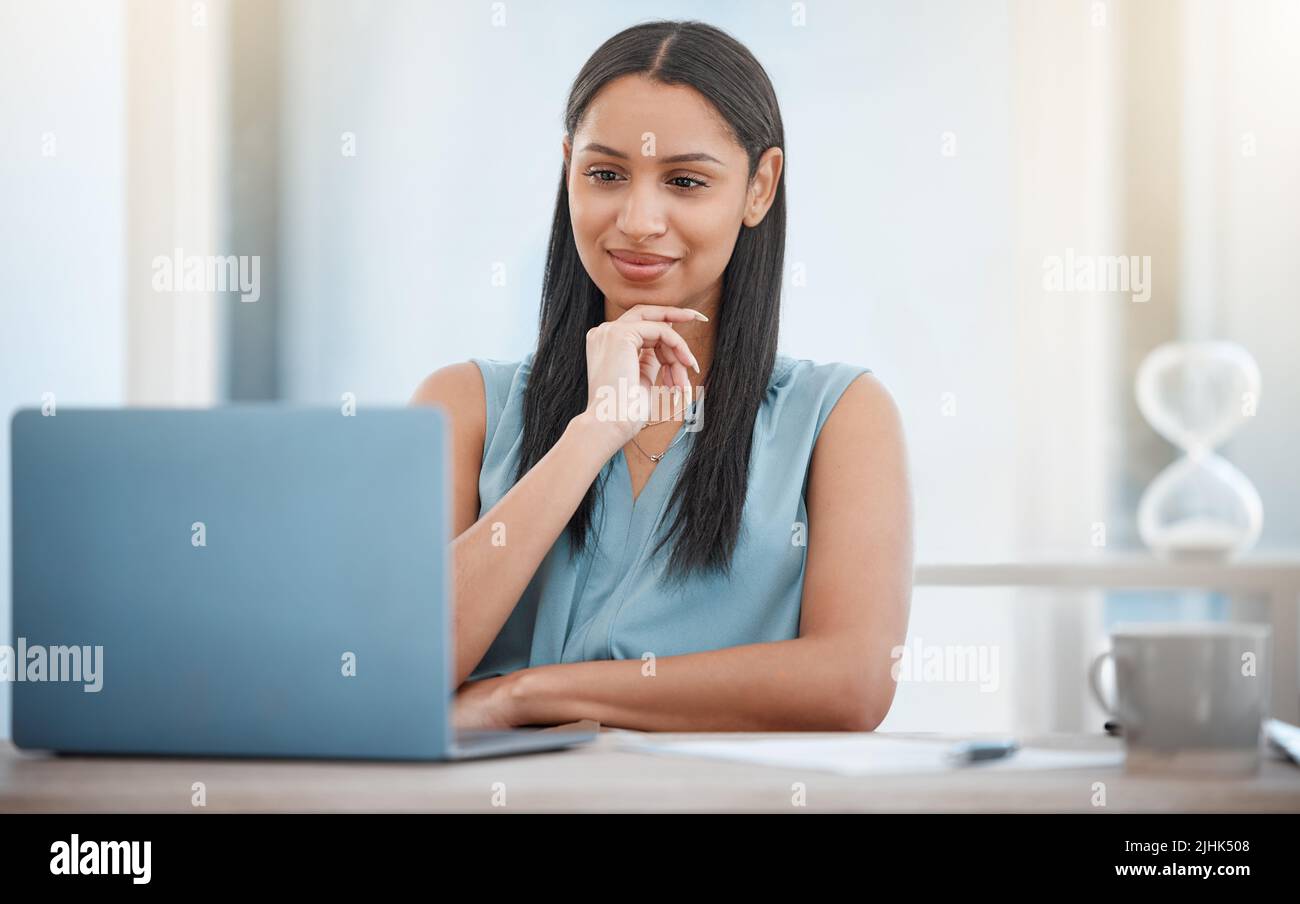Young mixed race business woman holding hand on chin while working on ...