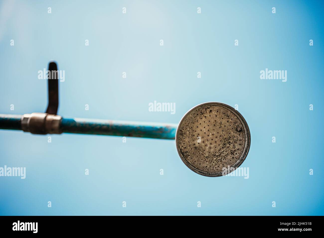Dry pipe shower head shot from below on hot summer day. No water and ...