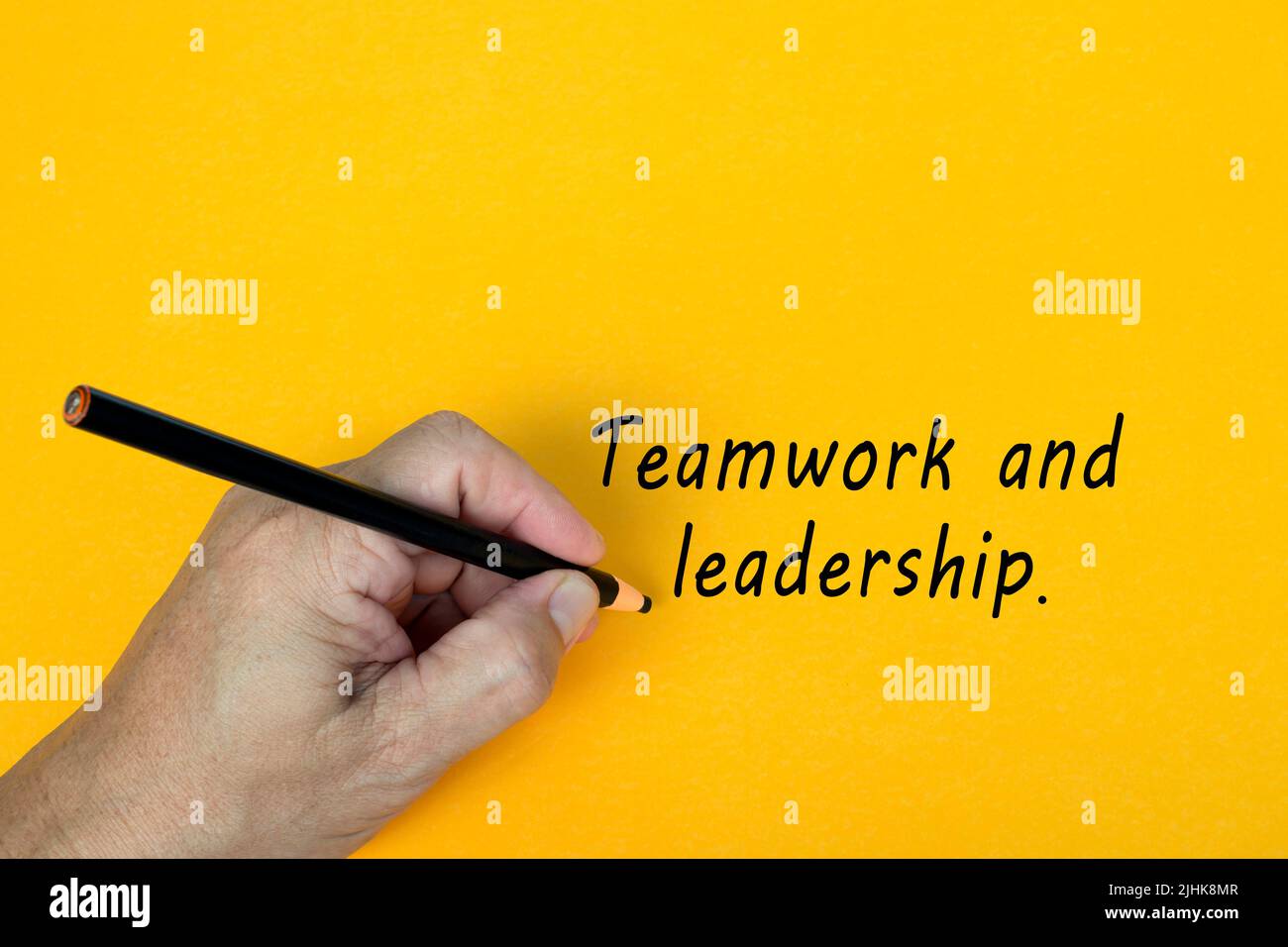 Male hand writes in black pencil the word TEAMWORK AND LEADERSHIP on a ...