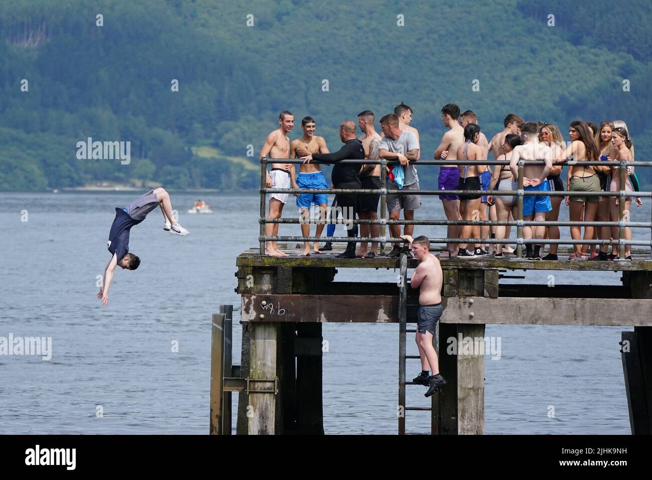 People jump from a pier into the water of Loch Lomond, in the village ...