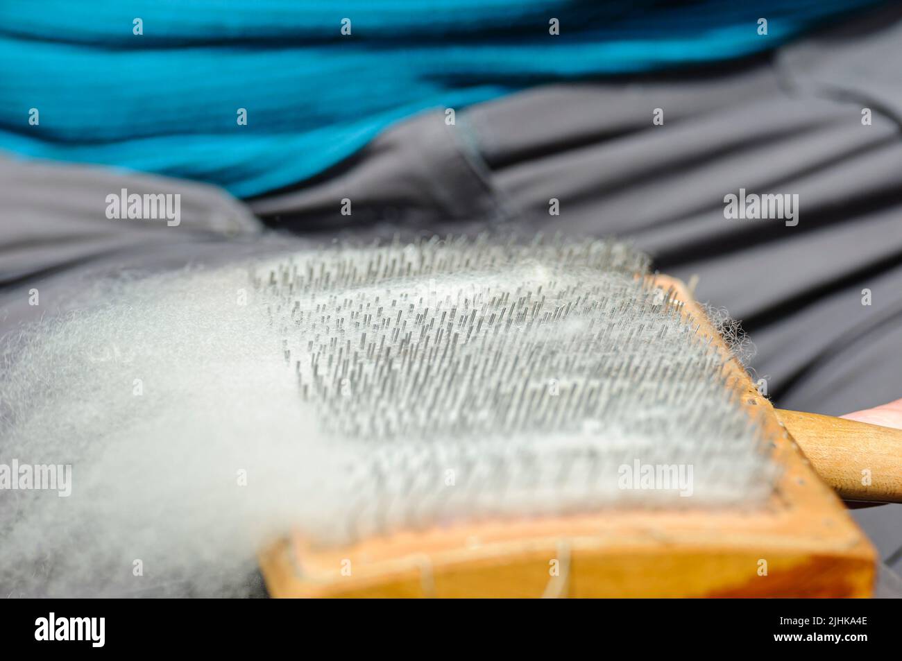 A woman uses traditional handcard combs to prepare sheep wool for ...