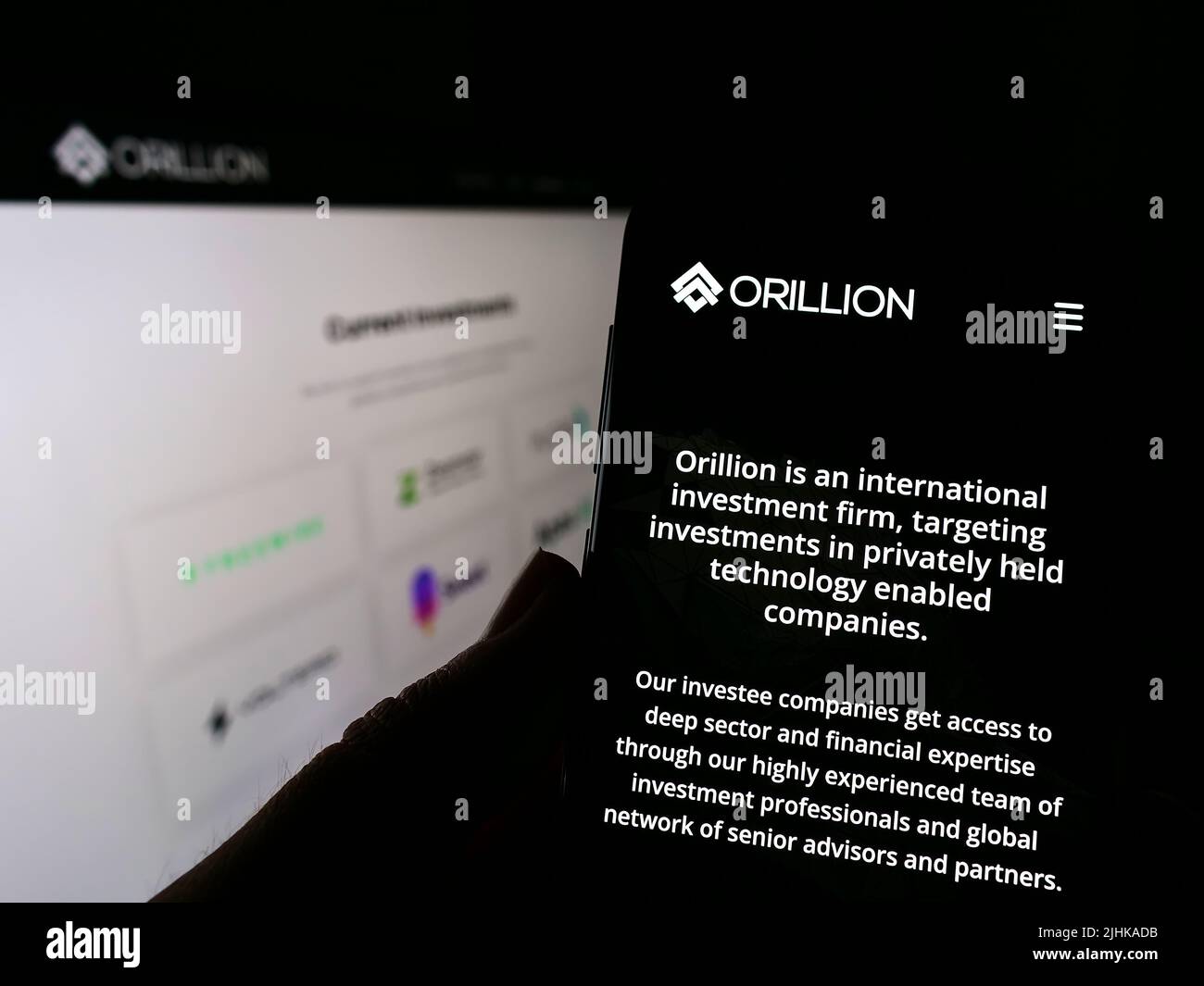 Person holding cellphone with website of investment company Orillion ...