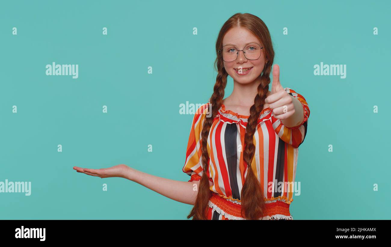 Beautiful redhead girl showing thumb up, pointing empty place ...