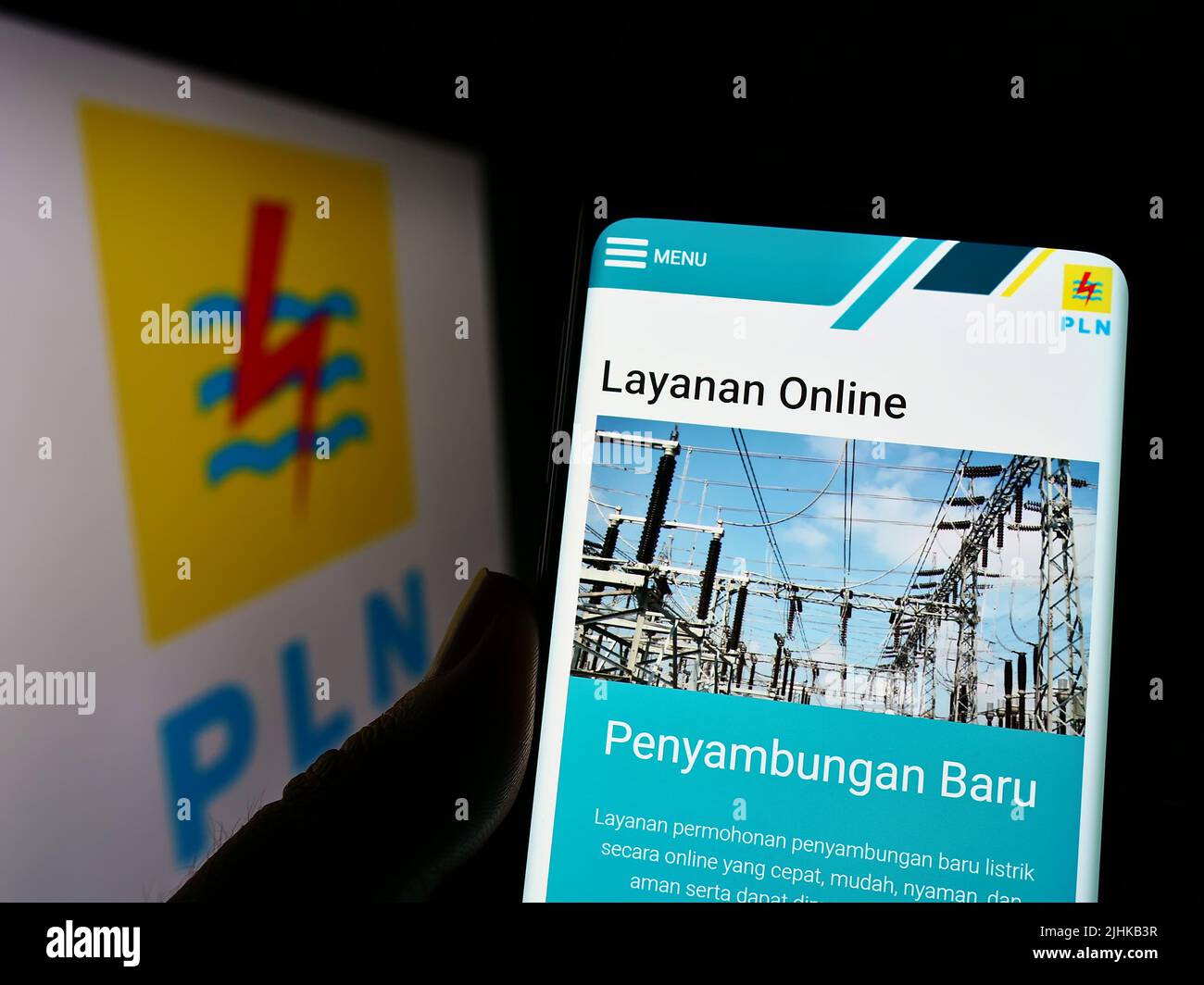 Person holding smartphone with website of company PT Perusahaan Listrik ...