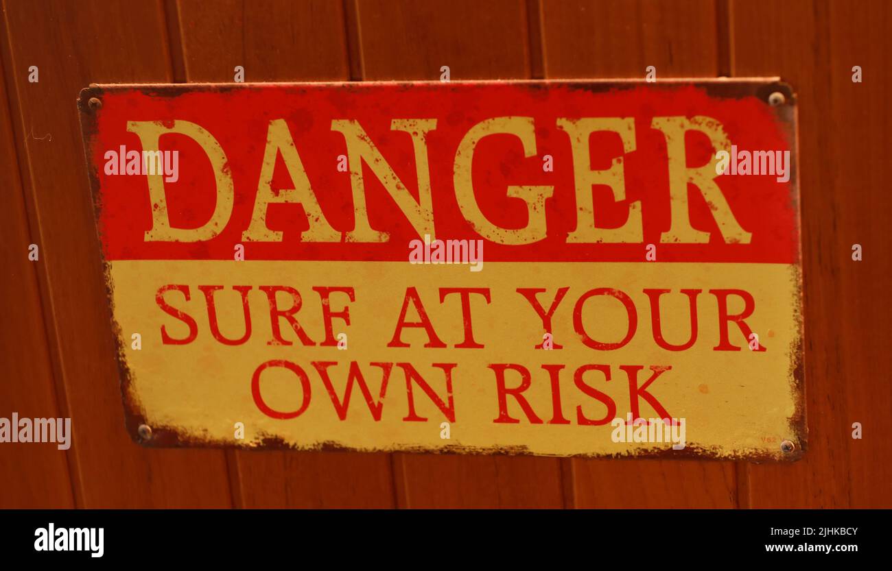 A yellow caution sign SURF AT YOUR OWN RISK of possible danger Stock ...