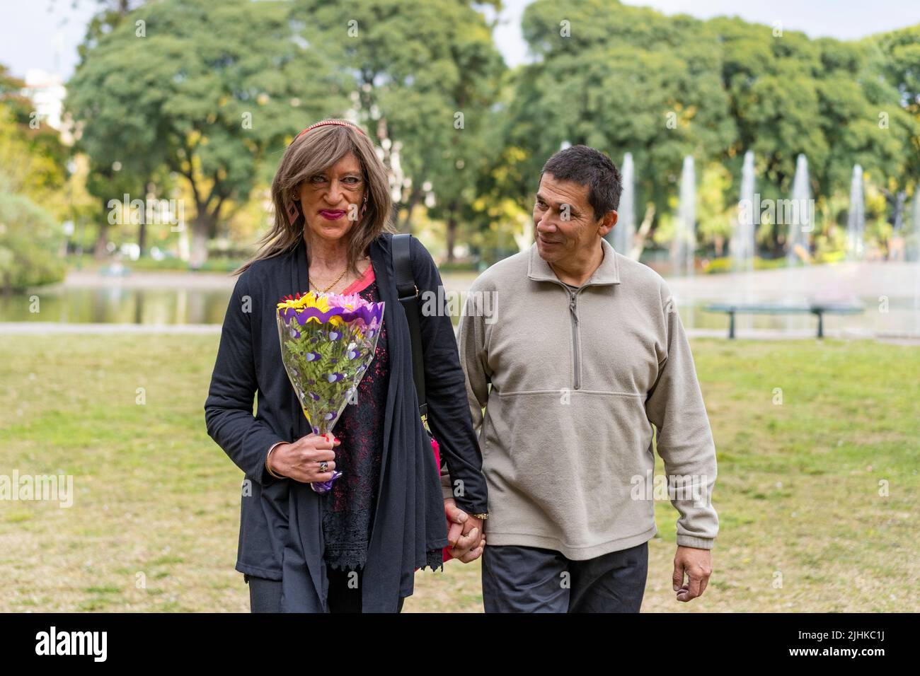 Mature transgender woman walking hand in hand with her boyfriend in a ...
