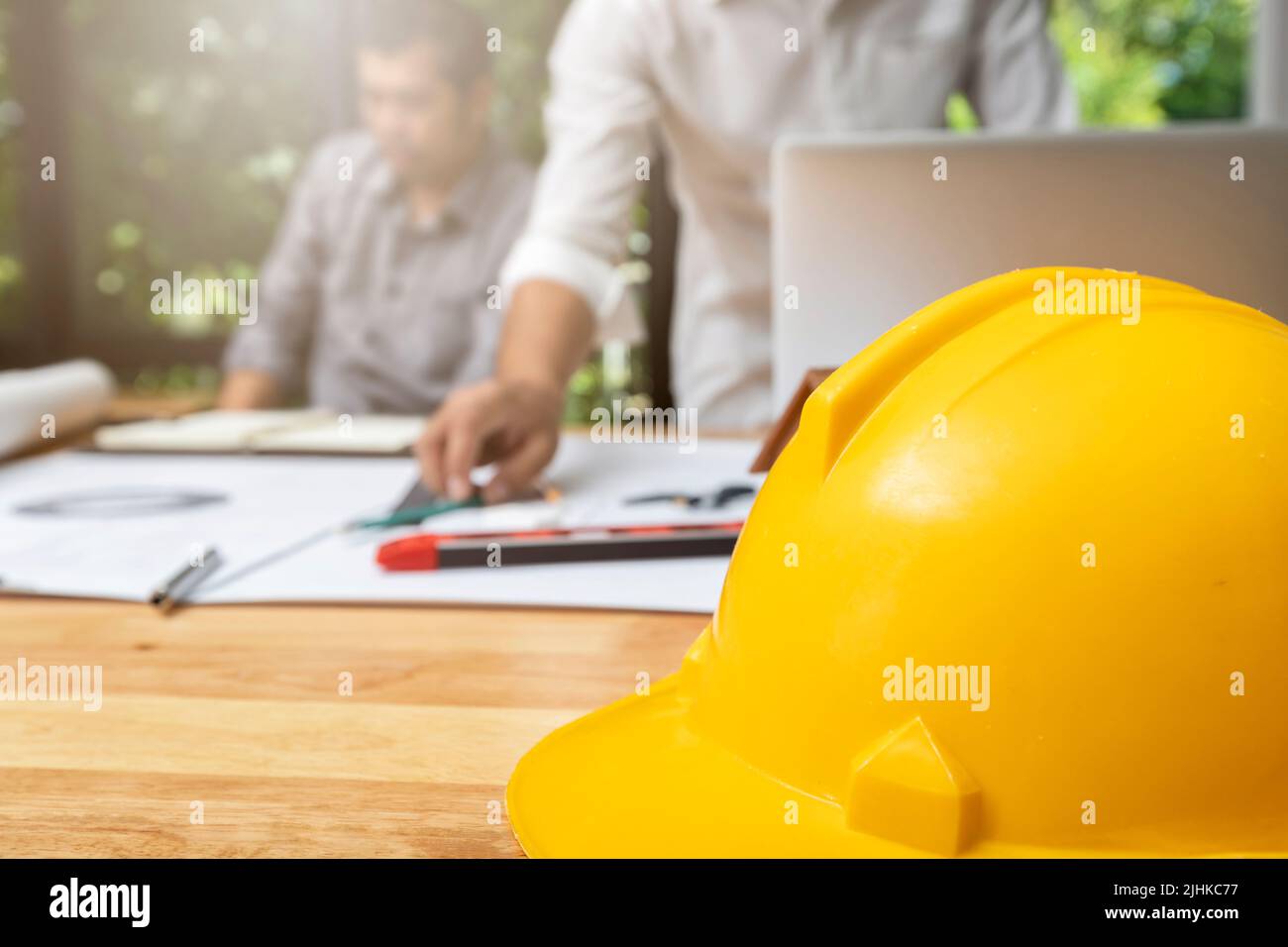 Close up image of a helmet on the desk with architects working with ...