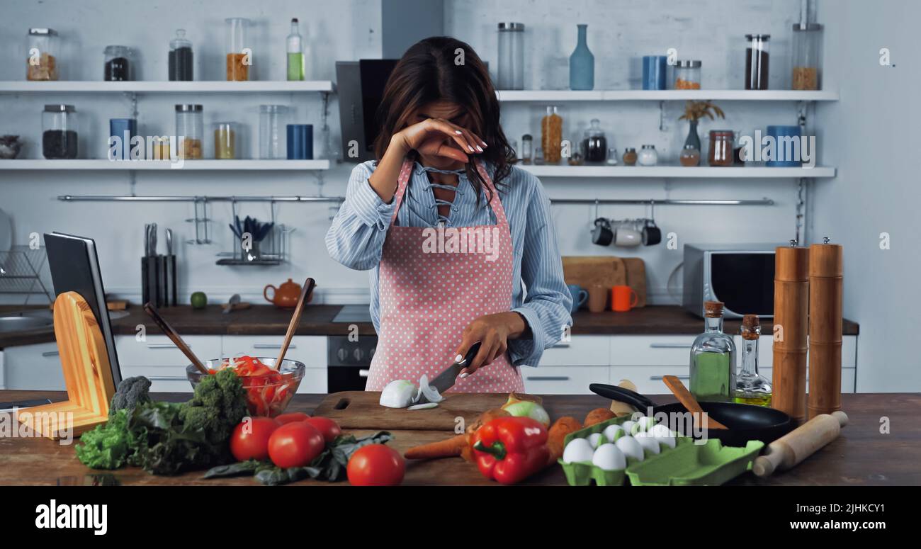 woman crying and wiping irritated eyes while cutting onion near fresh vegetables Stock Photo - Alamy