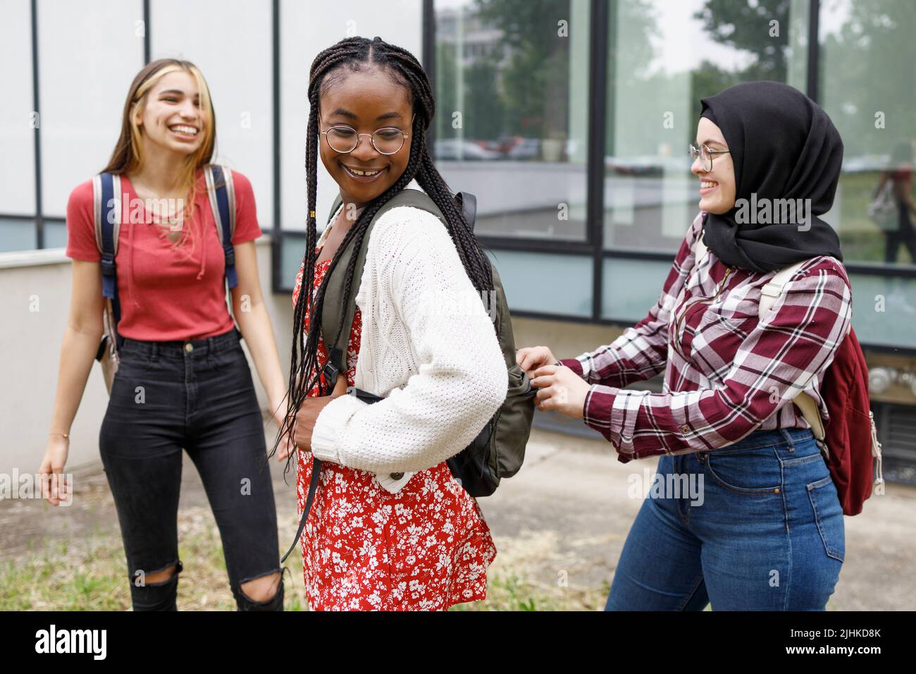 Young Arab woman helping her friend with her backpack Stock Photo - Alamy