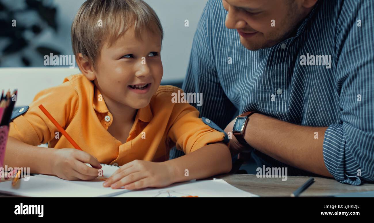 happy father looking at son drawing on paper at home Stock Photo - Alamy