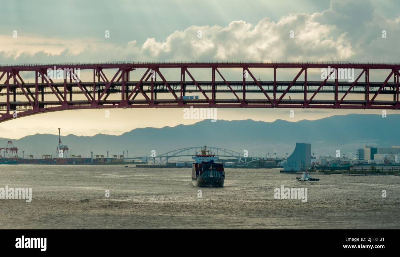 Container ship sails under bridge in harsh late-afternoon sun Stock ...