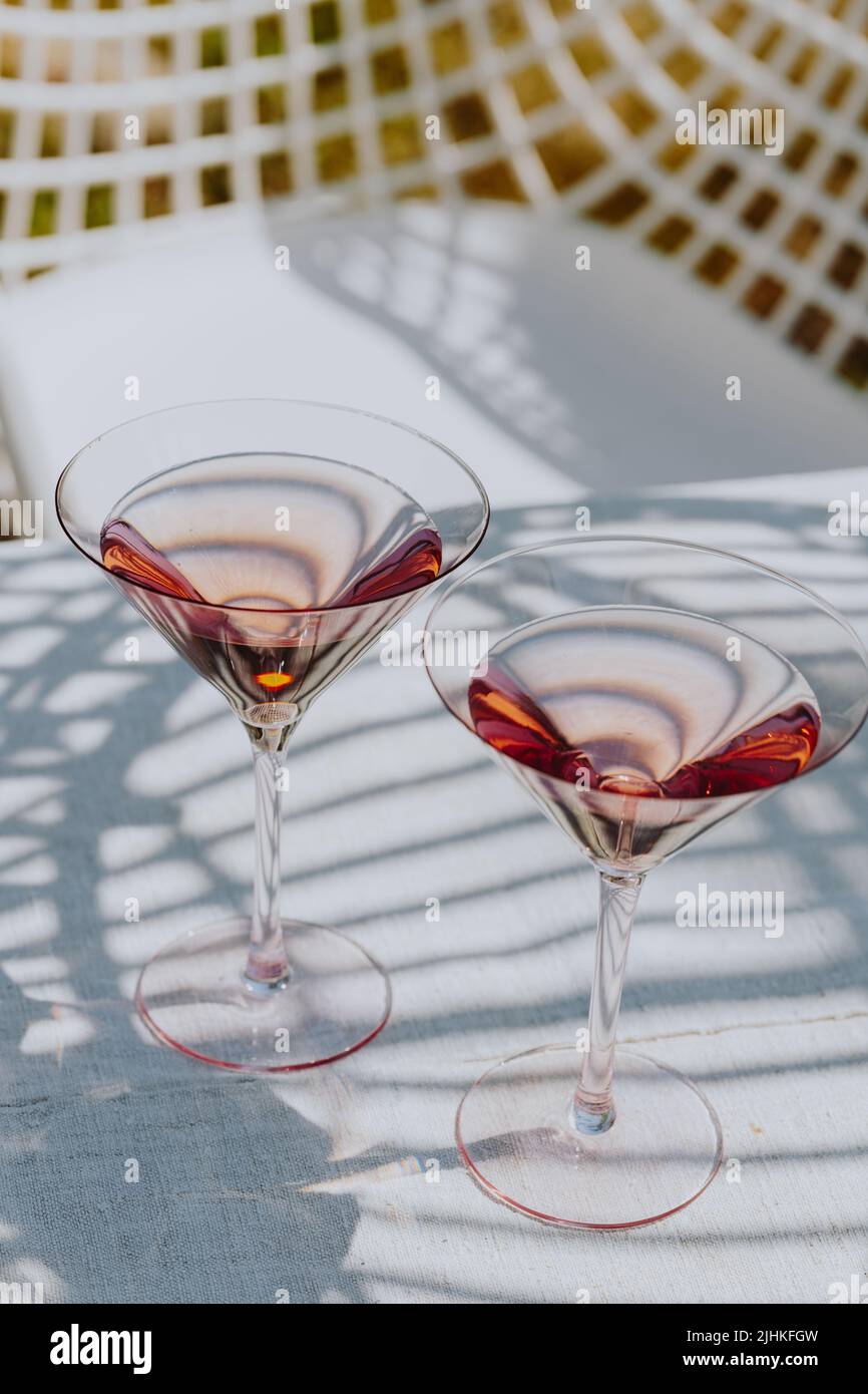 Two glasses with cold pink rose on a garden table in the summer sun ...