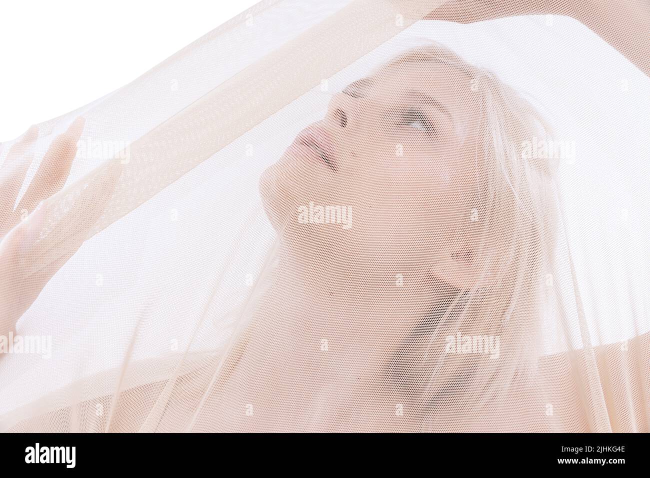 Young tender beautiful girl under transparent fabric, cloth isolated on ...