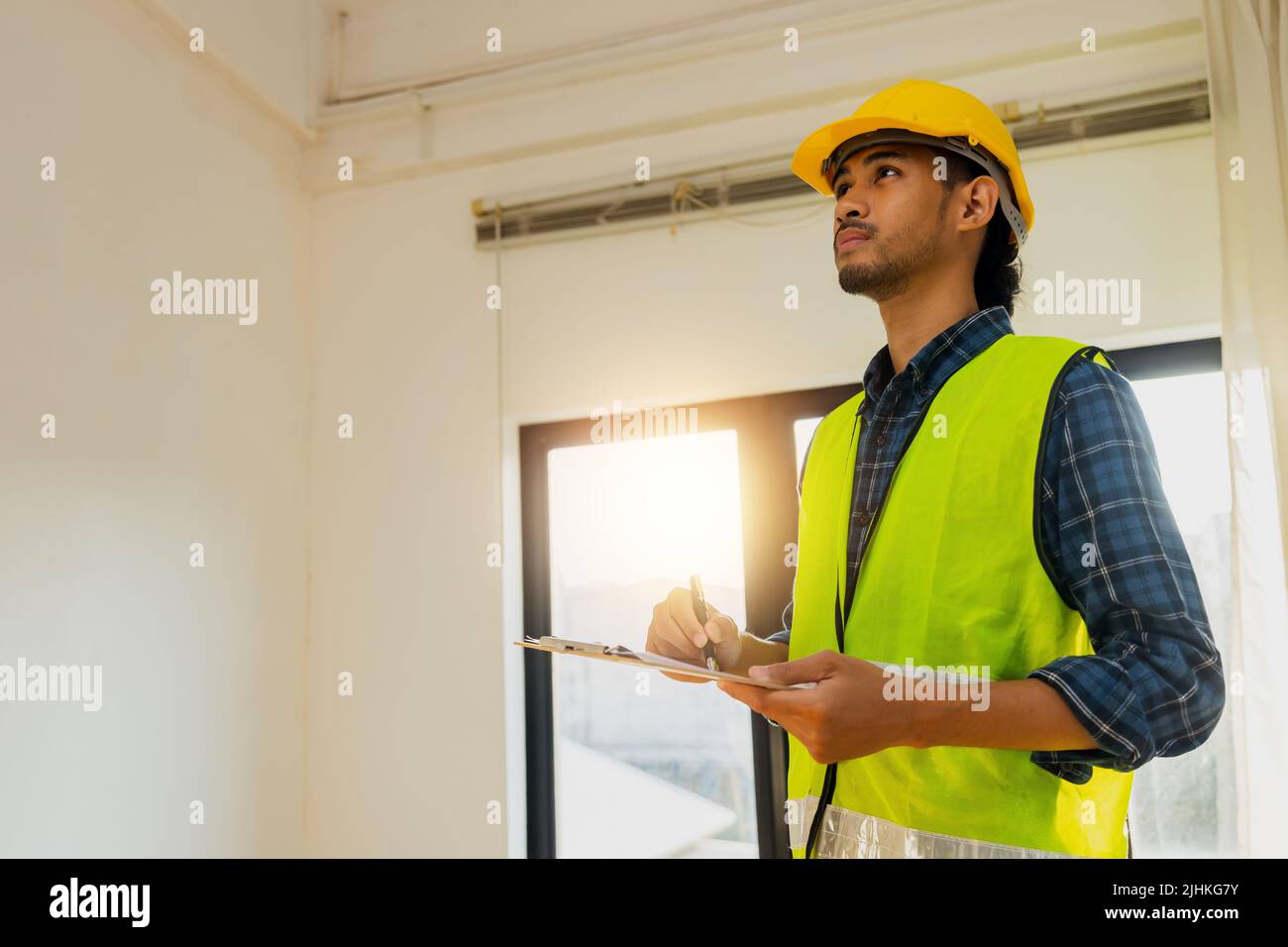 Asian inspector wear safety vest and checking list into clipboard ...