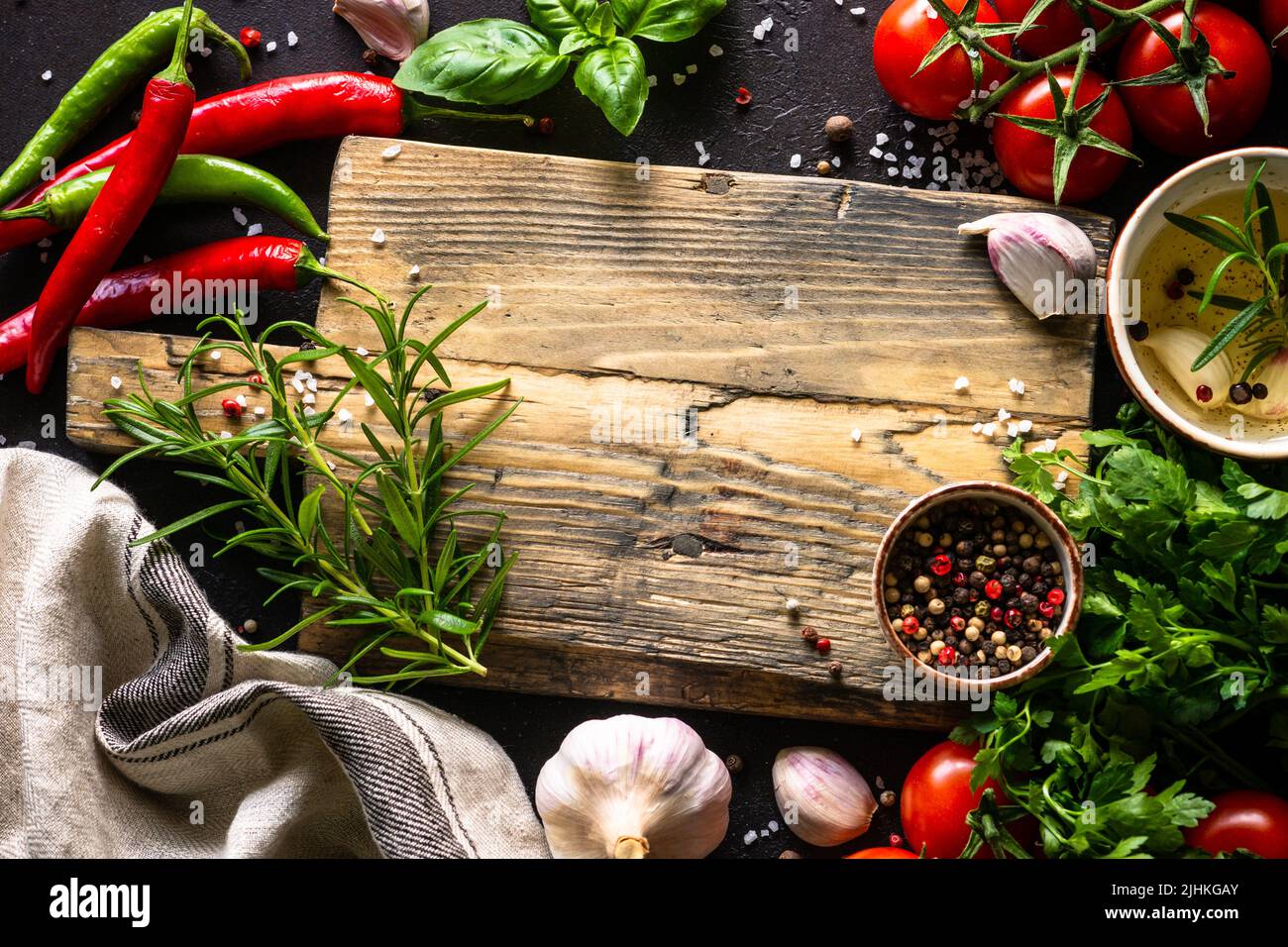 Food background. Oak cutting board, spices and vegetables at kitchen ...