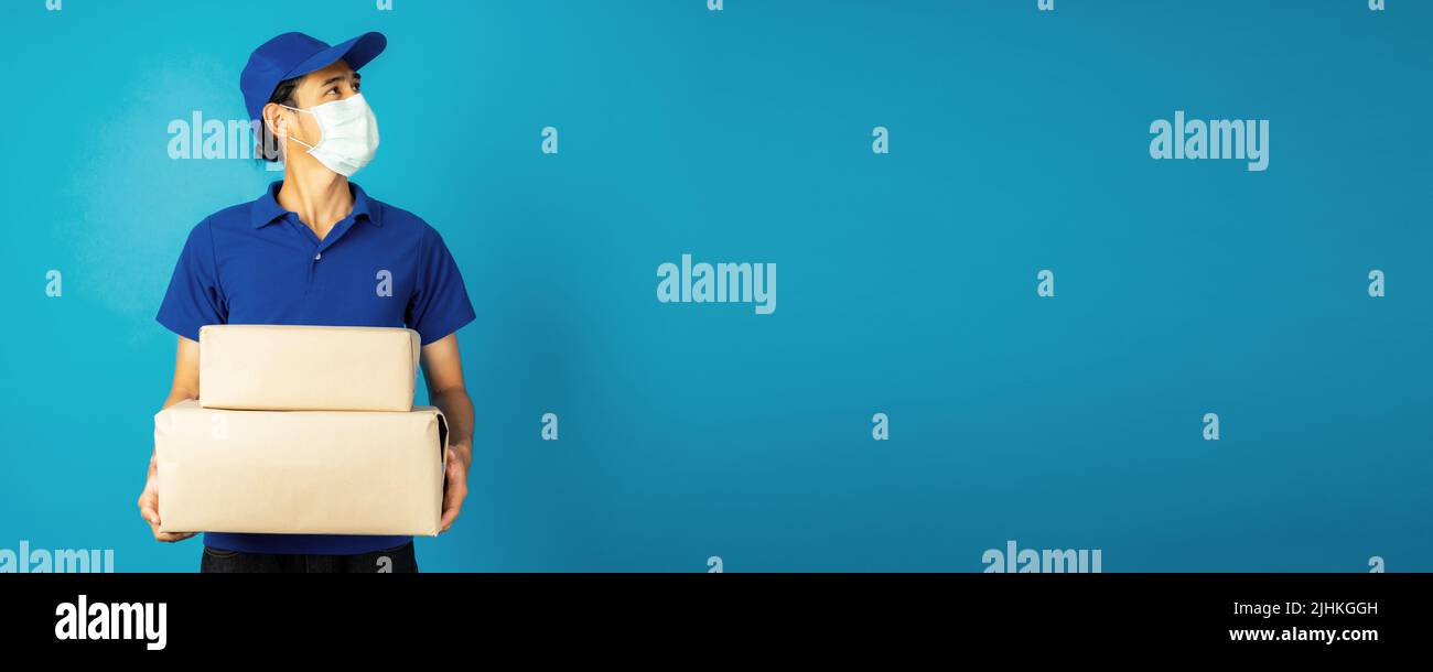 Portrait of excited delivery man in blue uniform holding parcel box ...
