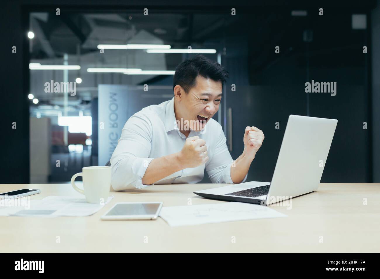 Portrait of successful Asian boss, businessman looking at laptop screen ...