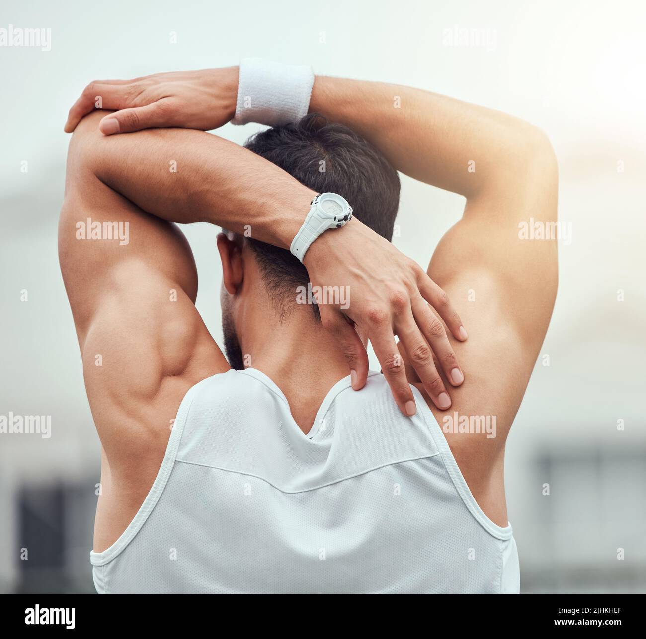 Rear view of unknown mixed race tennis player stretching arm and ...