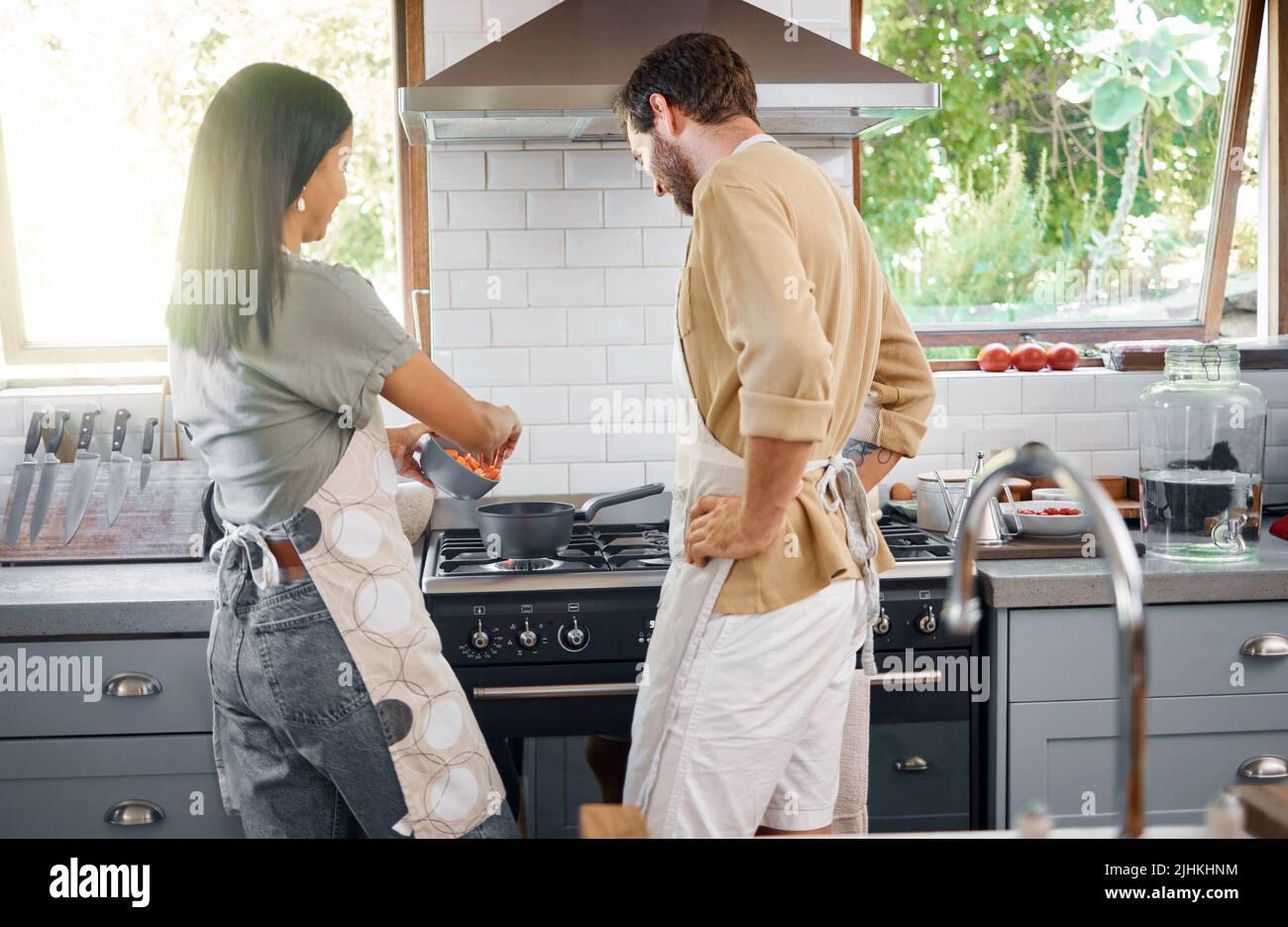 Rear view of young interracial couple cooking a healthy meal together ...