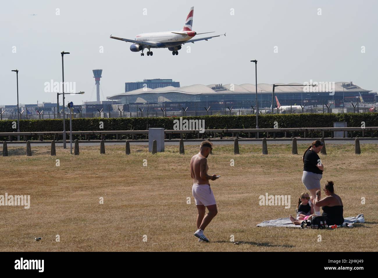 People enjoy the hot weather in a field beneath a British Airways ...