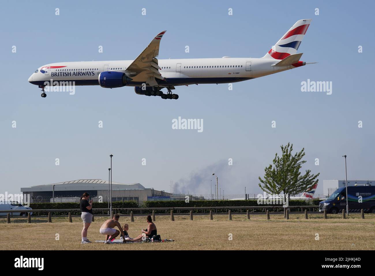 People enjoy the hot weather in a field beneath a British Airways ...