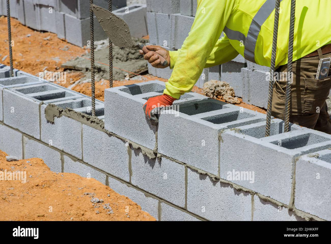 On a construction site, a mason is in the process of erecting a wall of ...