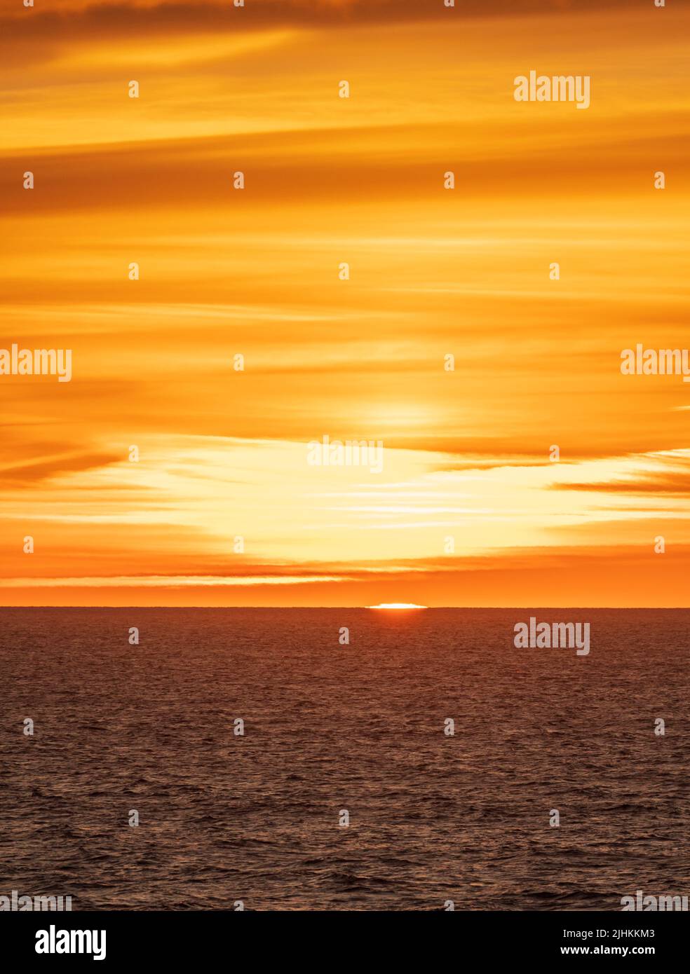 The final section of the sun drops below the water horizon with a ...