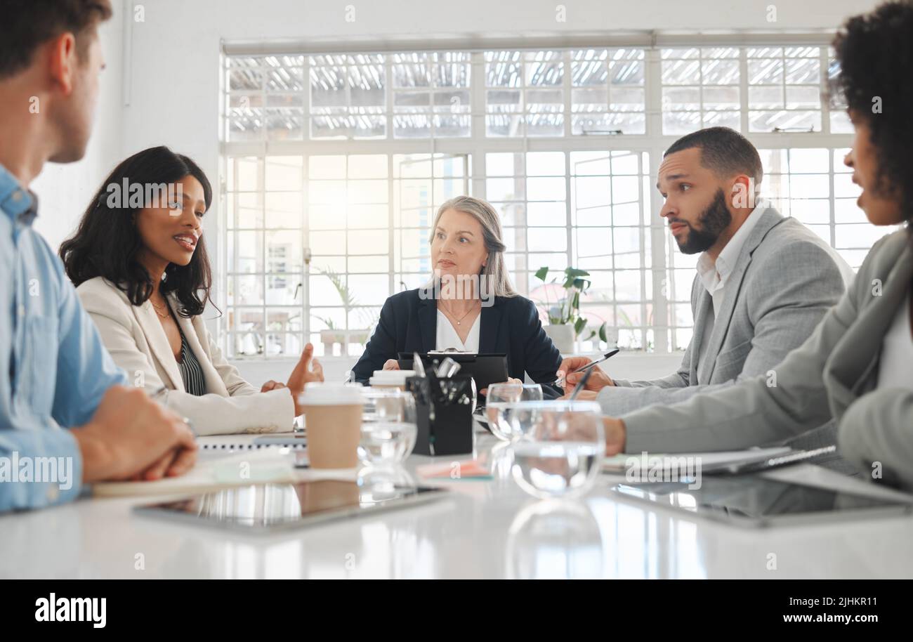 Group of five diverse businesspeople talking in a meeting together at ...