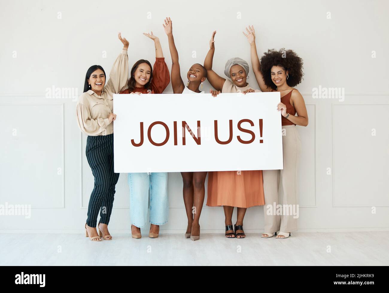Group of five diverse young businesswomen standing against a wall in an ...