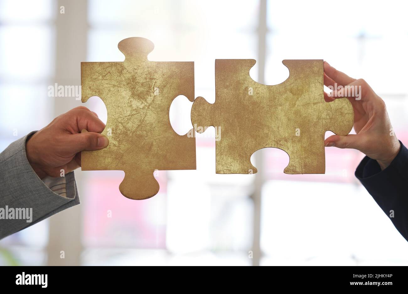 Two businesspeople holding and fitting puzzle pieces together in an ...