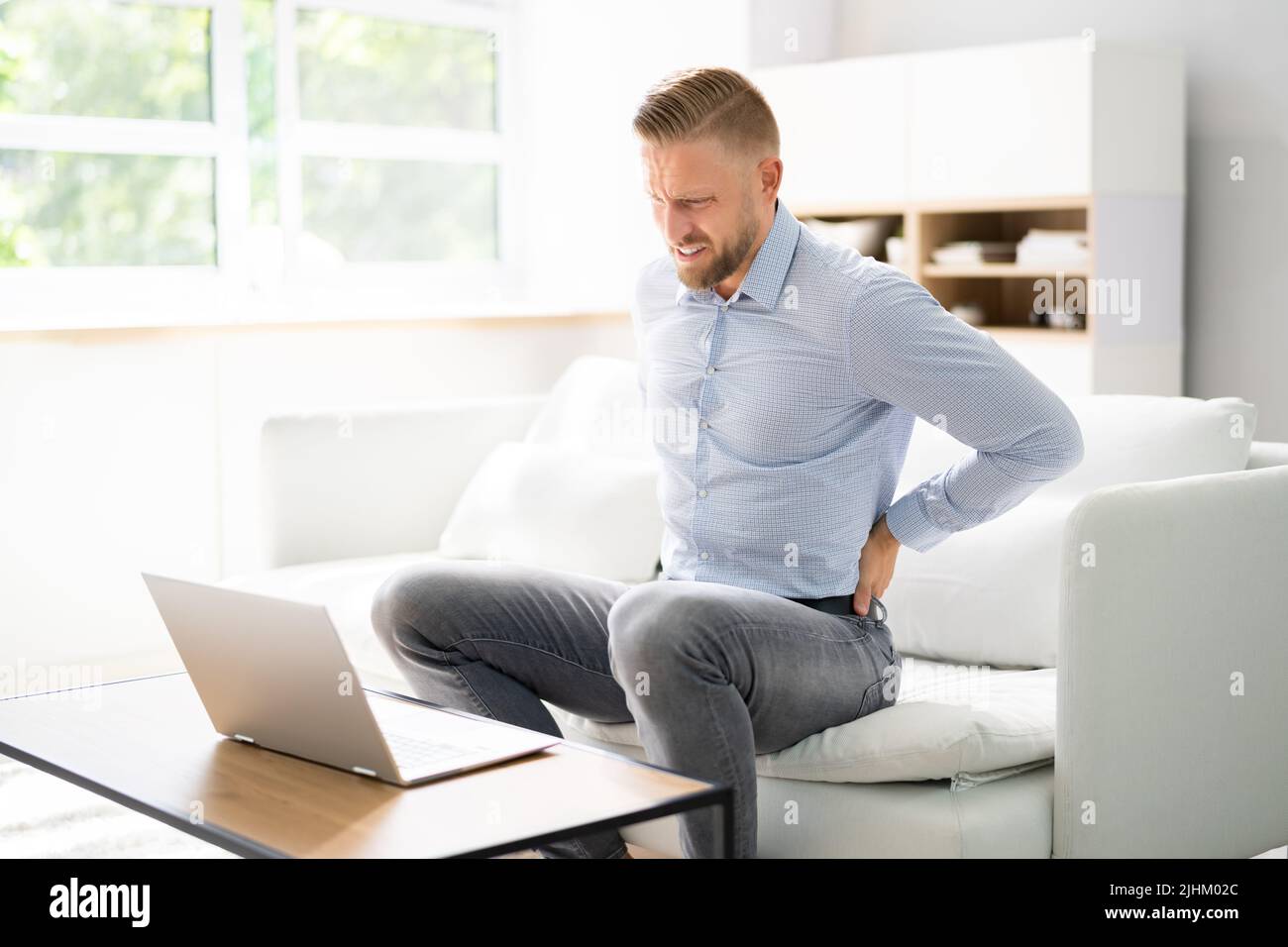 Back Pain Bad Posture Man Sitting At Home Stock Photo - Alamy