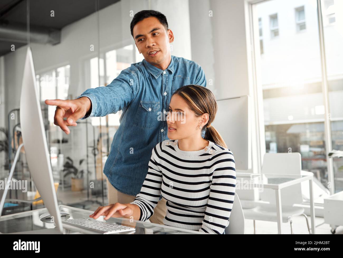 Two businesspeople working on a desktop computer together at work ...