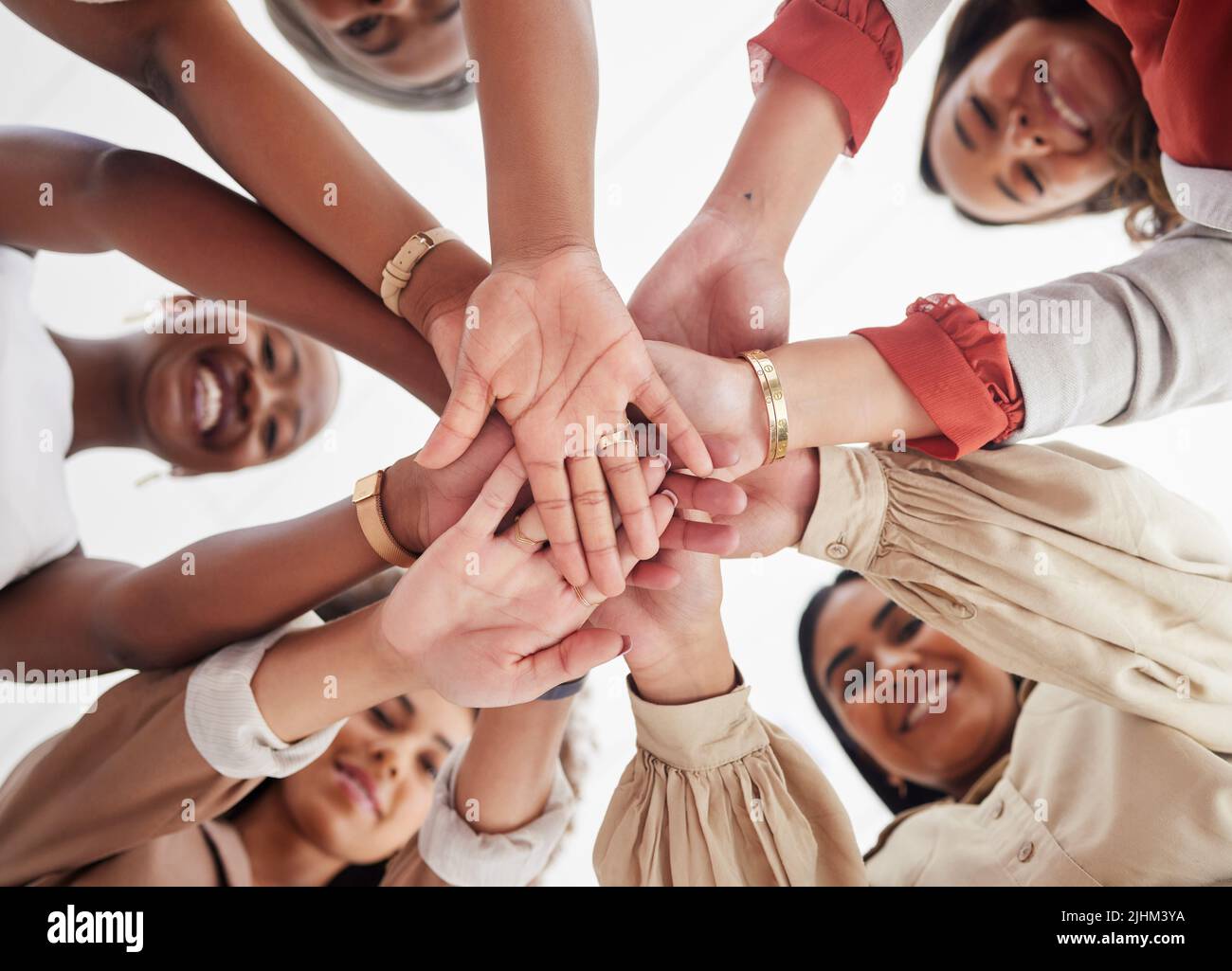 Low angle diverse group of ambitious smiling businesswomen huddled ...