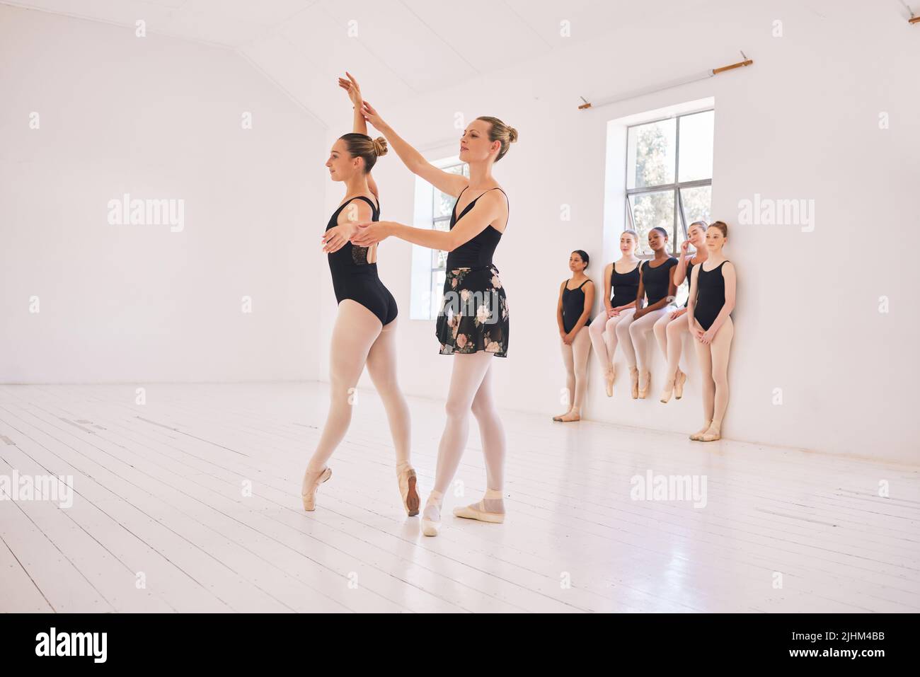 Young woman dance instructor teaching a ballet class to a group of a ...