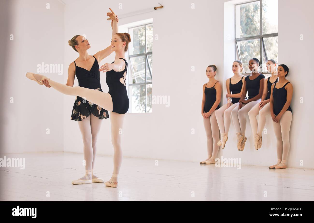 Young woman dance instructor teaching a ballet class to a group of a ...
