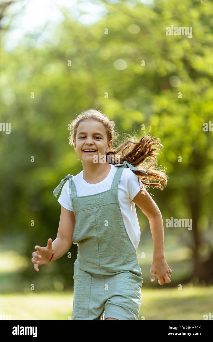 Cute little girl running happily in the park Stock Photo - Alamy