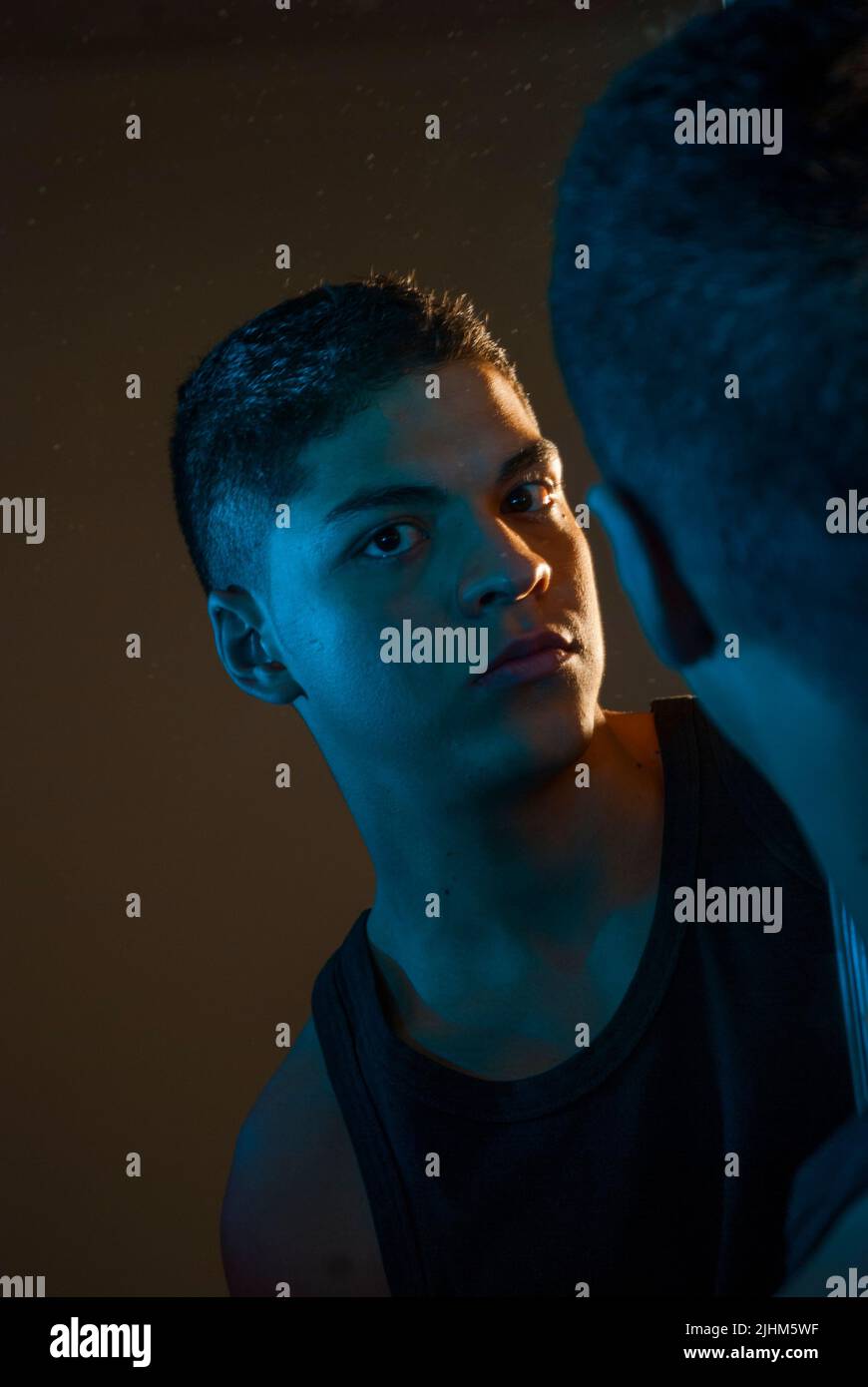 Young man and its reflection on mirror. Blue light Stock Photo - Alamy