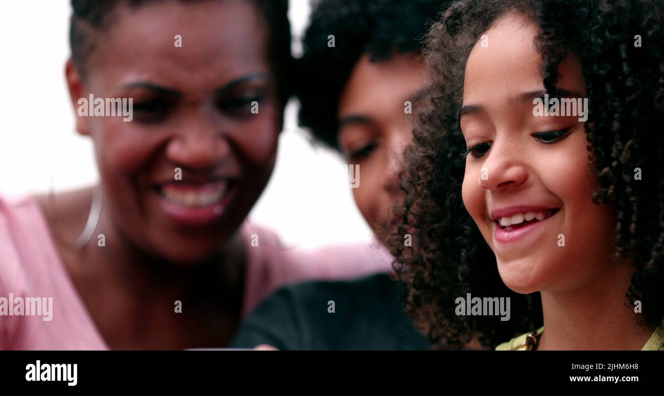 Happy multiracial family laughing and smiling together looking at phone ...