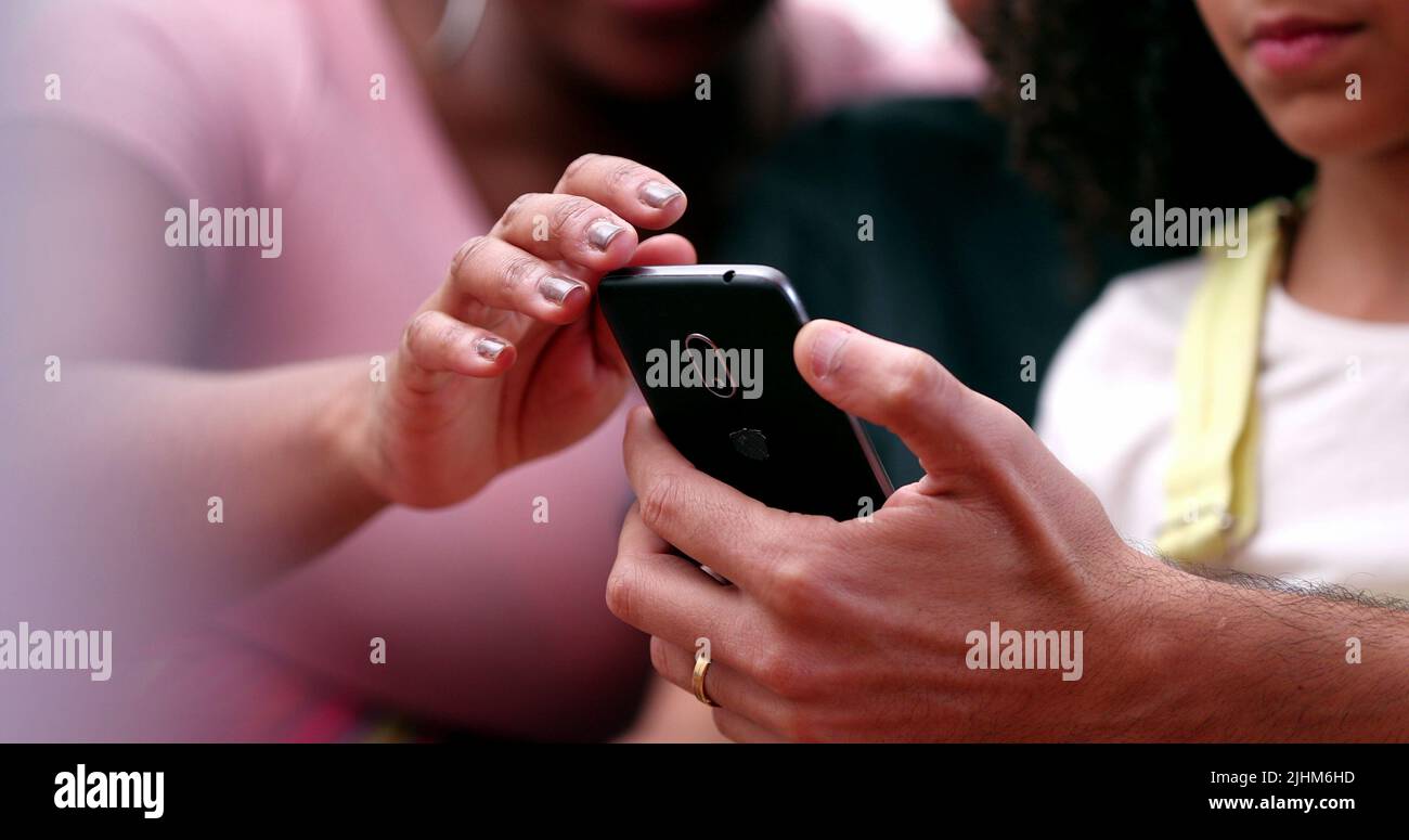 Happy multiracial family laughing and smiling together looking at phone ...