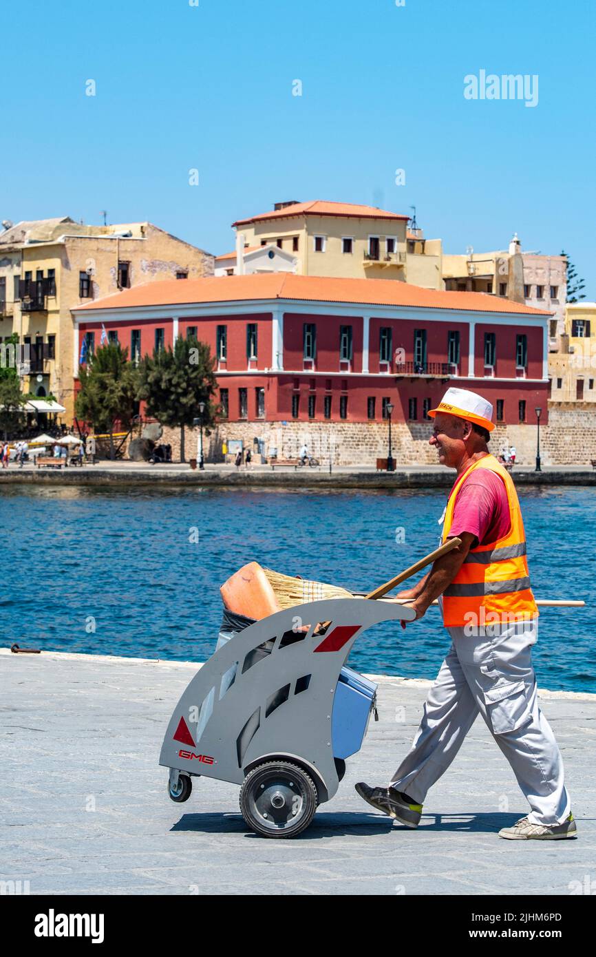 street cleaner pushing a barrow for litter collection on the quayside ...