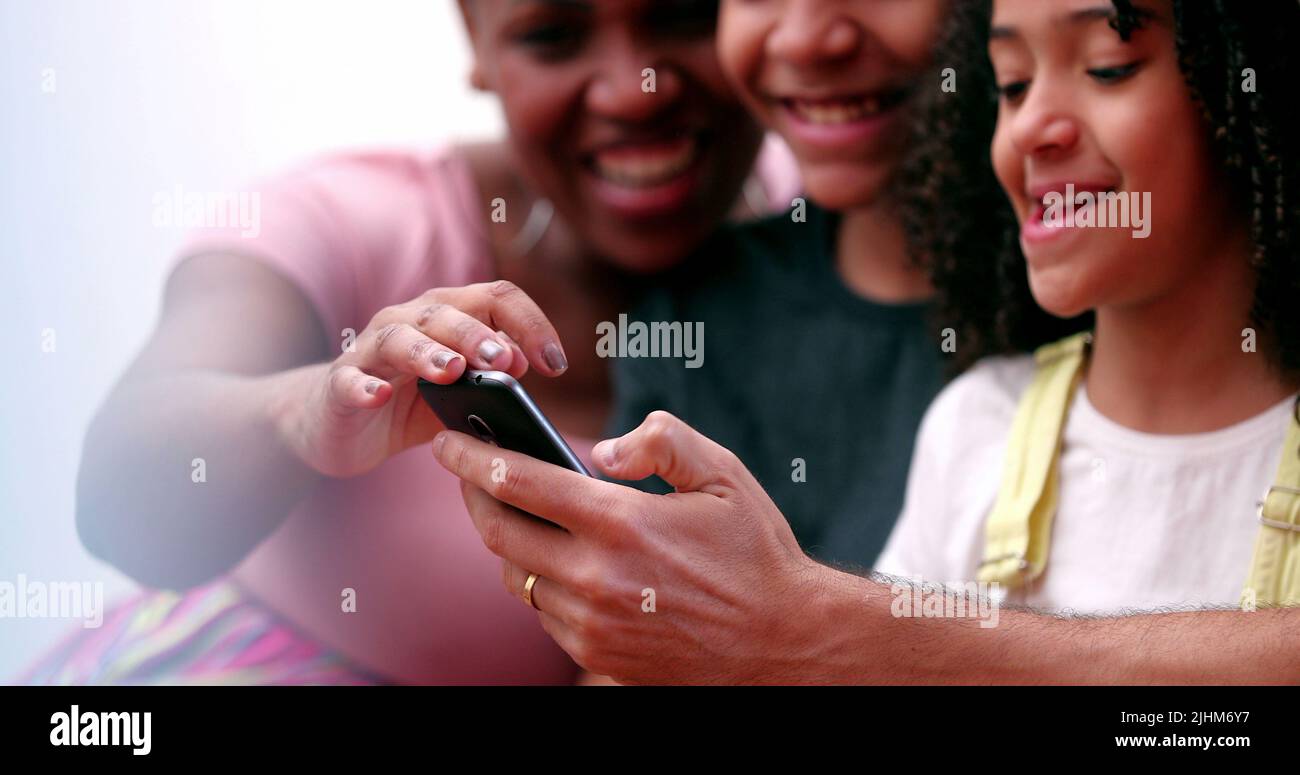 Happy multiracial family using smartphone Stock Photo - Alamy