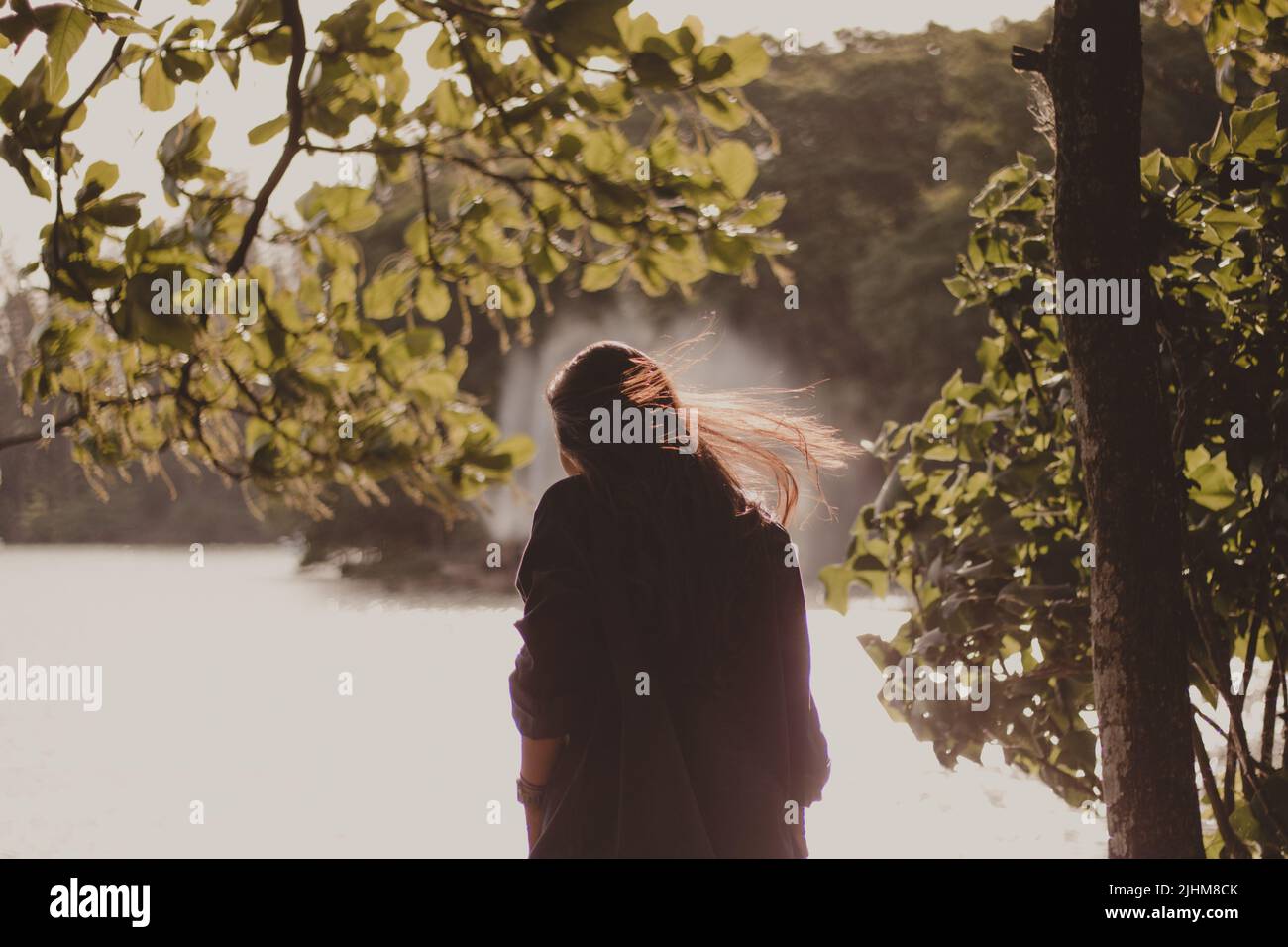 young woman standing backwards looking at the lake Stock Photo - Alamy
