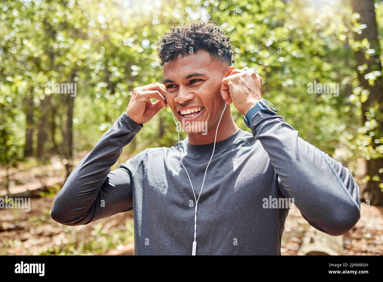 Young mixed race hispanic fit male athlete listening to music while on ...
