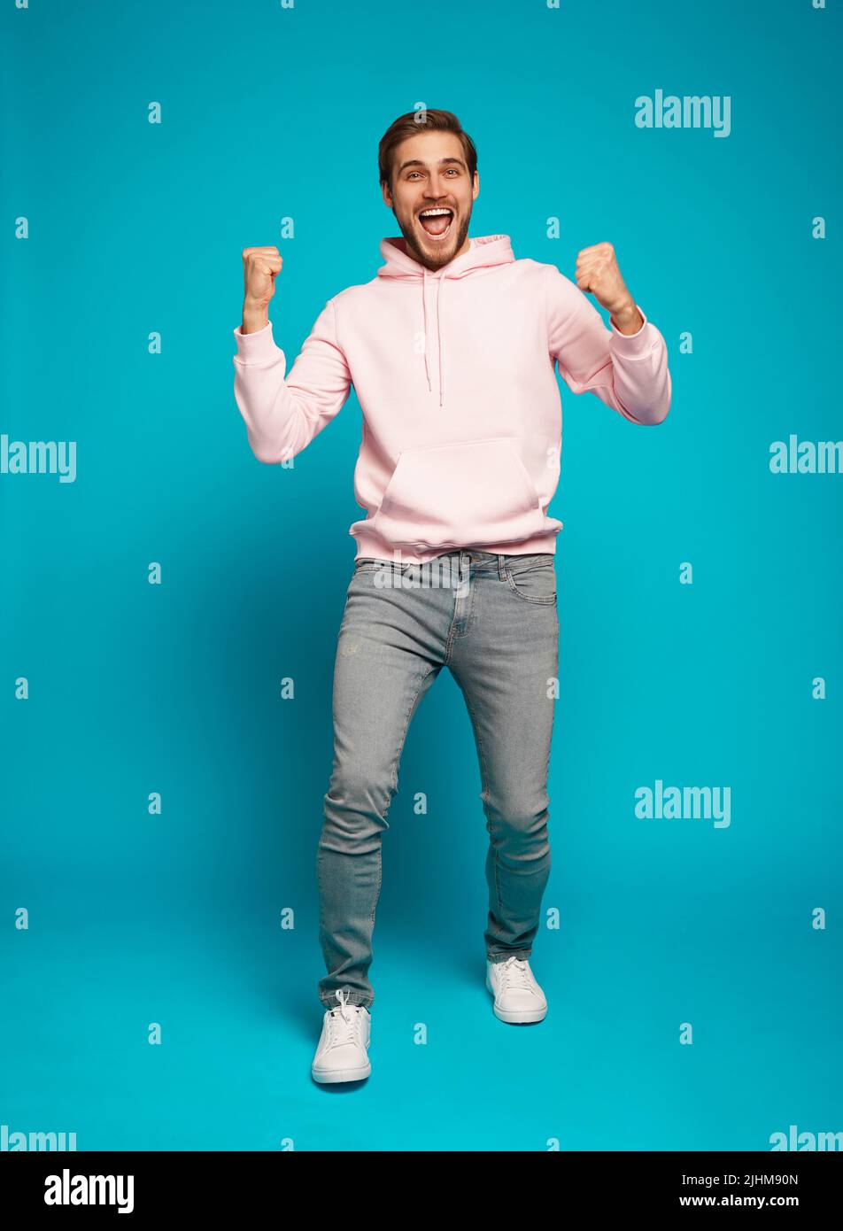 Full length of a cheerful young man standing and celebrating success ...