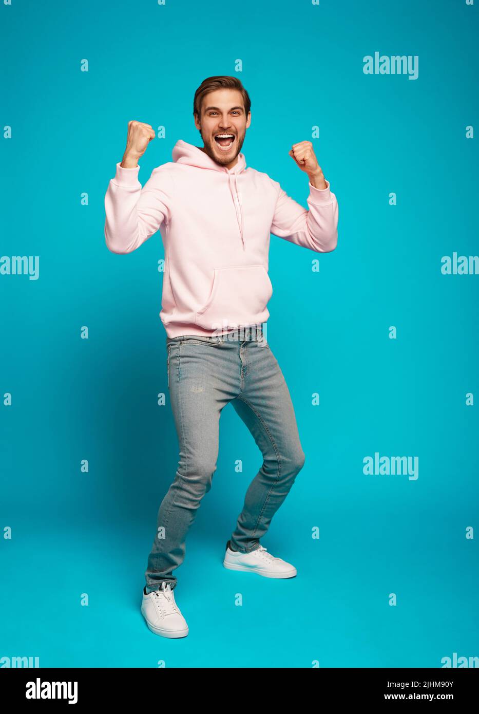 Full length of a cheerful young man standing and celebrating success ...